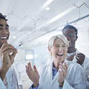 Diverse group of happy scientists clapping hands while writing and ...