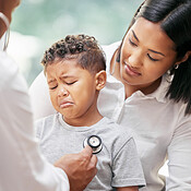 Doctor examining sad little boy by stethoscope. Sick boy crying while ...