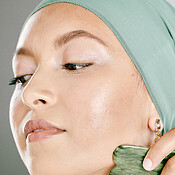 Woman using a facial stone on her face. Beauty model doing her morning ...