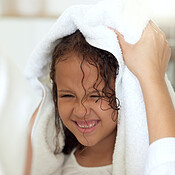 Happy, carefree and smiling little girl drying off after a bath, shower ...