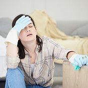 Tired, stressed young woman with headache doing spring cleaning chores ...