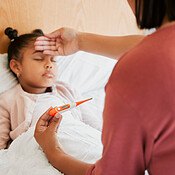 Unwell, exhausted and sick little girl in bed with concerned mother ...