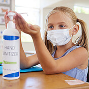 Little student sanitizing hand to protect from covid, wearing a mask ...