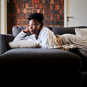 Bored, depression and isolation with black woman lying on her sofa ...