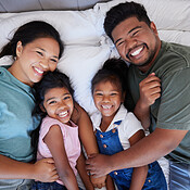 A happy black family in bed, mom and dad hold children with love. In ...