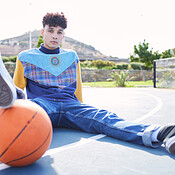 Basketball, fashion and portrait of a trendy model sitting on the floor ...