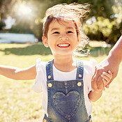 Happy, child in sun and walk in a nature park with a smile with parents ...