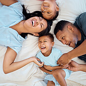 Happy, fun and family bedroom bed with mother, father and kids laughing ...