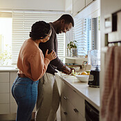 Black couple, cooking and helping with food in kitchen at home while ...