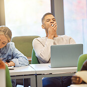 Education, man and student tired, classroom and studying for exams ...