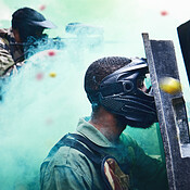 Paintball team, shooting together and war game with shield, mask or ...