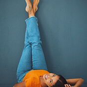 Woman on floor, smile on face with legs up on wall background and ...