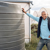 Farmer, portrait and water tank in farming liquid or soil hydration for ...