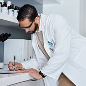 Science, writing and man in laboratory for research, medical report and ...