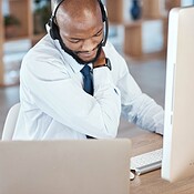 Black man, call center and neck pain by computer for tech support ...
