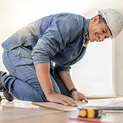 Handyman, wood flooring installation and happy at workplace, industry ...