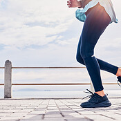 Legs of woman, fitness and running at promenade beach for energy ...