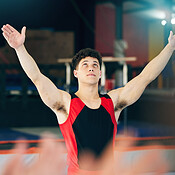 Gymnastics, performance and celebration of man in stadium after stunt ...