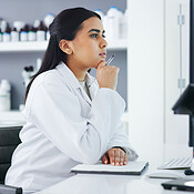 Young scientist using a computer and microscope in a lab. Female ...