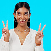Happy woman, peace and face wink in studio, blue background and color ...