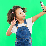 Silly little girl, selfie and peace sign on green screen with goofy facial expressions against a ...