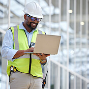 Laptop, engineering man and construction worker for online project ...