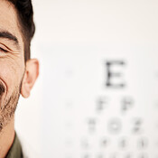 Half face, optometrist and man with eye chart in hospital for vision ...