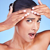 Shock, pimple and young woman in studio for cosmetic, beauty and ...