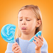 Children, candy and a sad girl with a broken lollipop on an orange ...