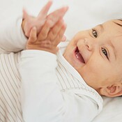 Infant baby, clapping hands and bed with parent, care or learning with ...