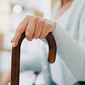 Hand, walking stick and closeup for woman in nursing home, living room or hospital for mobility ...