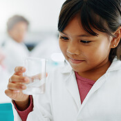 Science, glass beaker and a student girl in a classroom for education ...