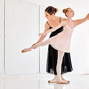 Ballet class, child learning dance and teacher with student in studio ...