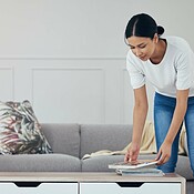 Cleaning, living room books and hygiene woman tidy apartment, home or ...