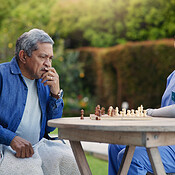 Happy woman, nurse and senior playing chess in nature for elderly care ...