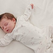 Sweet, sleeping and newborn baby on a bed at a home in the bedroom for ...