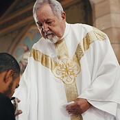 Religion, church and man with priest for communion for ceremony ...