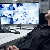 Security guard, computer screen and tired by cctv monitor for ...