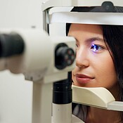 Woman, optometry and slit lamp for test, vision or care for wellness ...