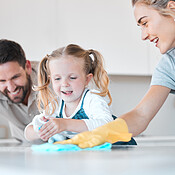 Little girl helping her parents clean. Caucasian family cleaning their ...
