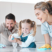 Little girl spraying the kitchen counter. Caucasian family cleaning the ...