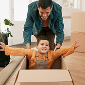 Father, boy and push box in new home with smile for plane, spaceship or ...