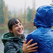 Smile, couple and hug in rain outdoor for hiking with love, freedom and ...
