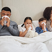 Family, sick and blowing nose in bed for allergies, flu and common cold ...