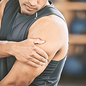 Fit man experiencing arm cramp. Bodybuilder with shoulder pain in the gym. Athlete with physical ...