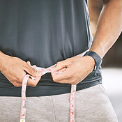 Hands of a bodybuilder measuring his waist. Fit trainer using tape ...