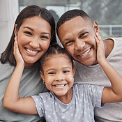 Happy and affectionate young mixed race family of three sitting on a sofa in the living room at ...