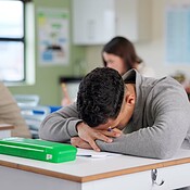 Exam, boy and tired on desk with stress, overwhelmed and brain fog in ...