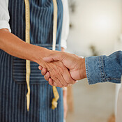 Two clothing designers shaking hands while working together at a shop ...