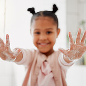 One mixed race adorable little girl washing her hands in a bathroom at ...